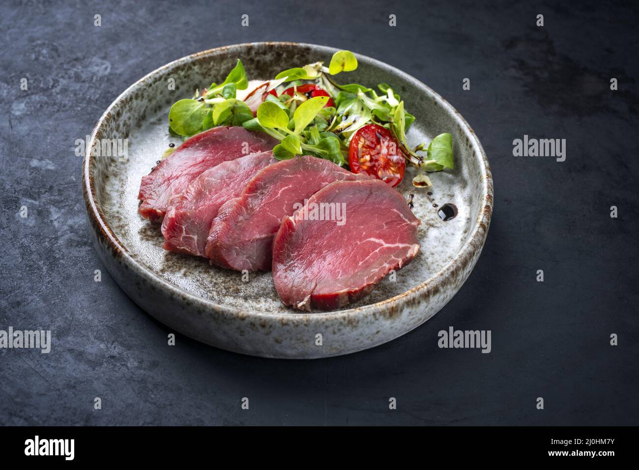 Modern style gourmet raw Japanese tataki beef filet with lettuce and ...