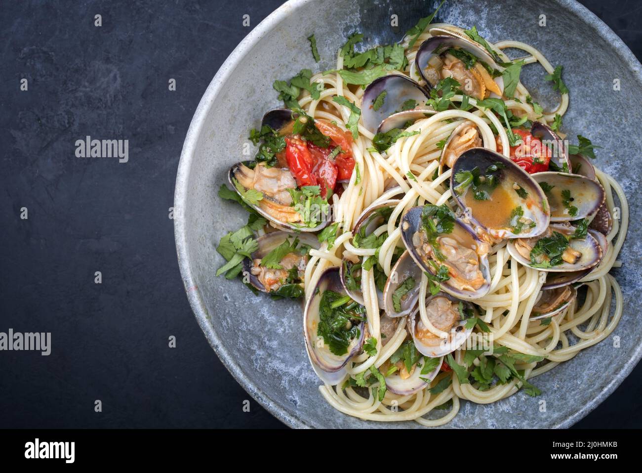 Spaghetti alle vongole with tomato in seafood jus served as top view at ...