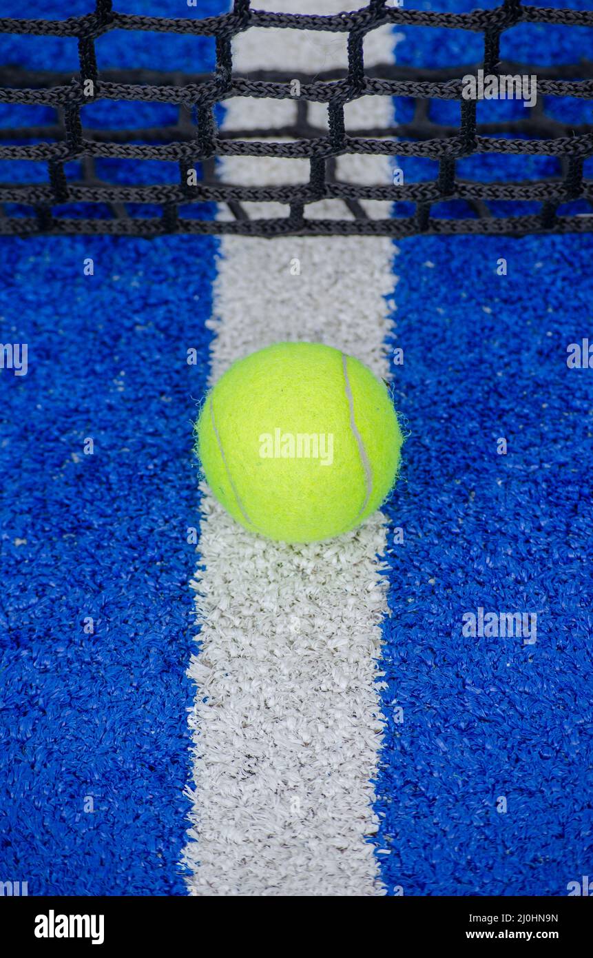 Paddle tennis ball on the service line and near the net of a blue ...