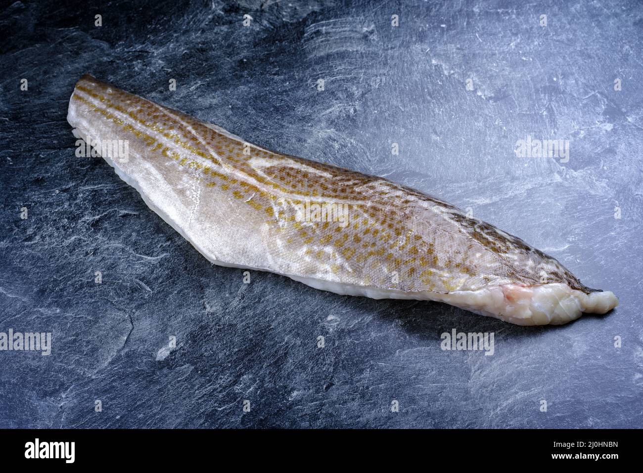 Raw Norwegian skrei cod fish filet with skin offered as close-up on ...