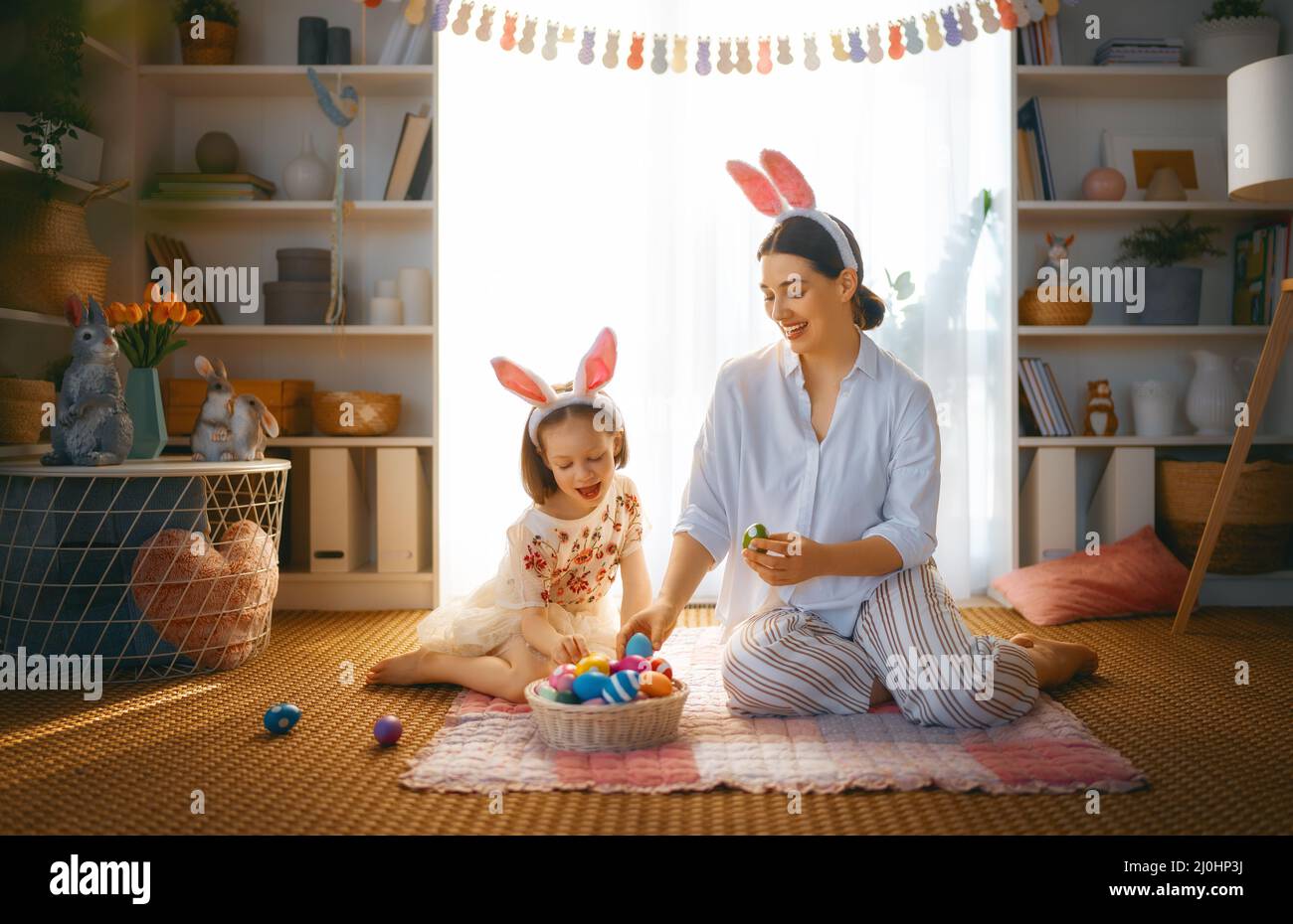 Happy holiday! Mother and her daughter with painting eggs. Family celebrating Easter. Cute ...