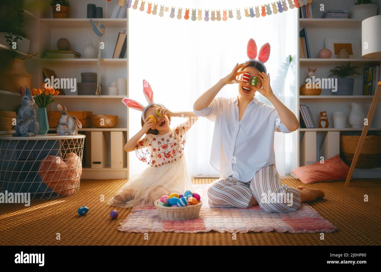 Happy holiday! Mother and her daughter with painting eggs. Family celebrating Easter. Cute ...