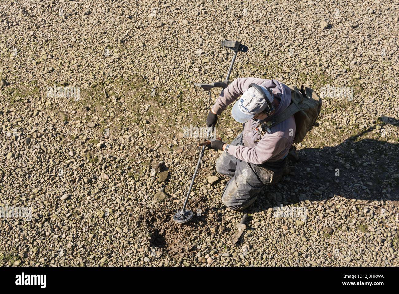 A single white male metal detecting on the gravel foreshore of the ...