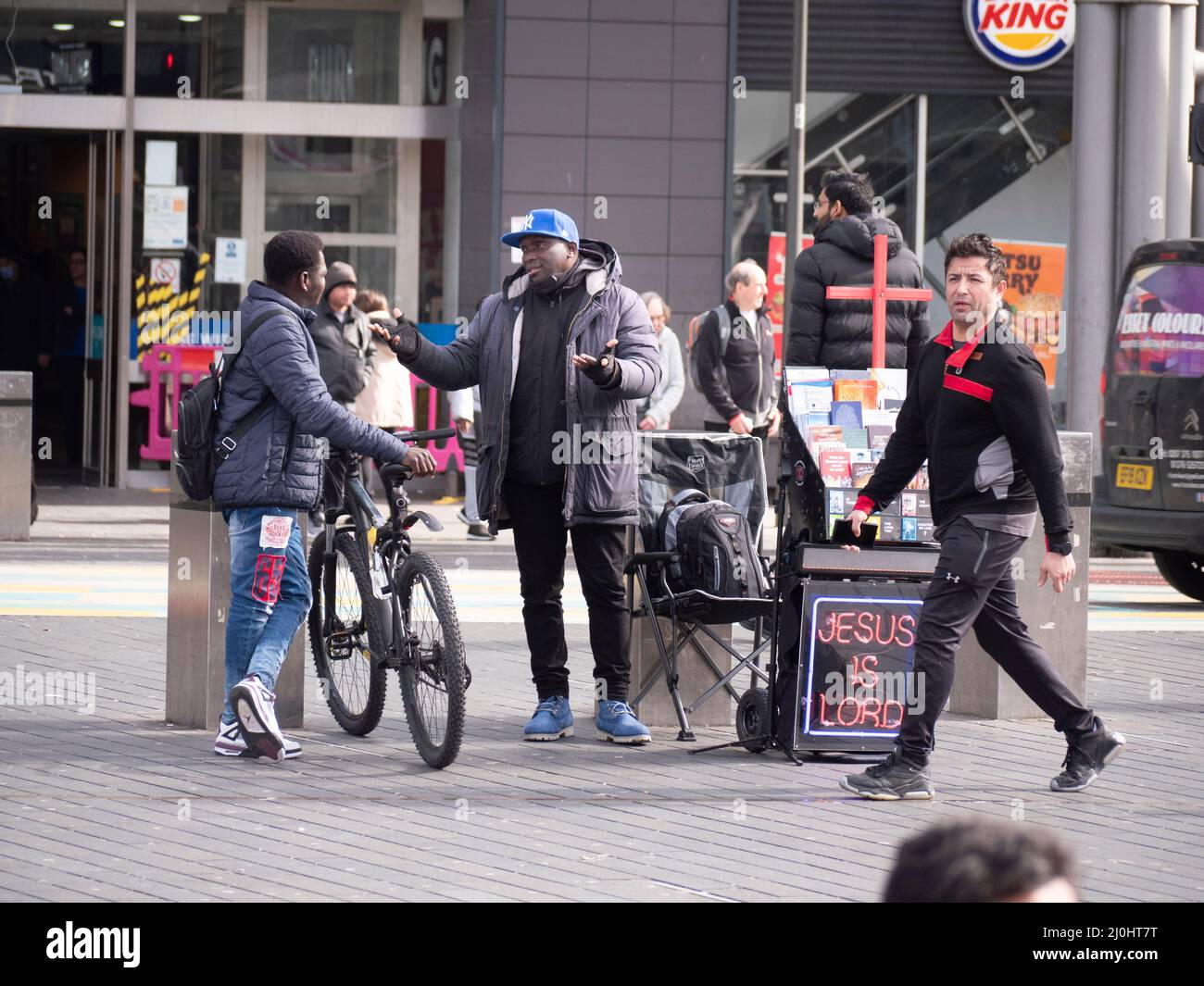 Christian street preacher, with Jesus is Lord neon sign, preaching to ...