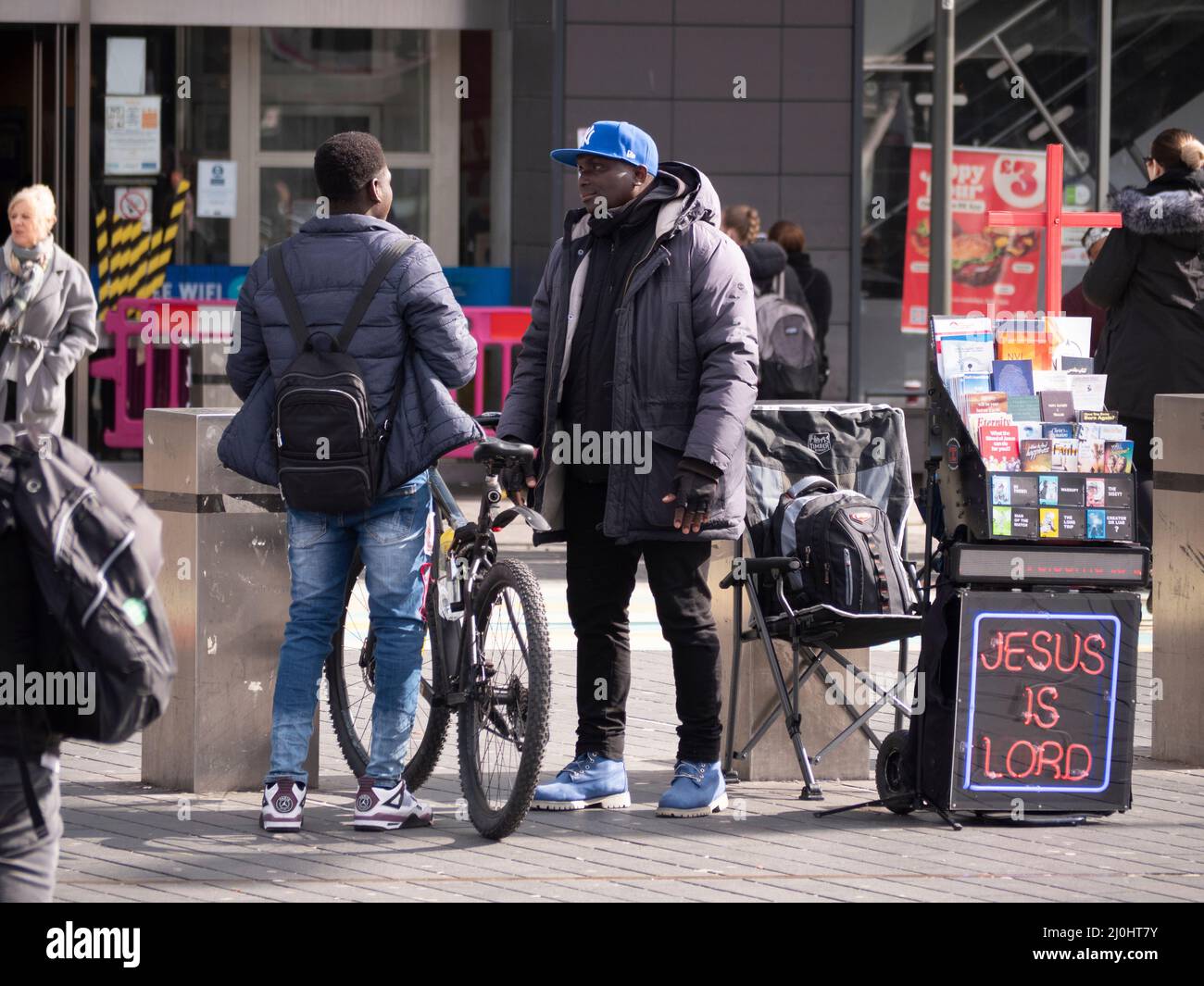 Christian street preacher, with Jesus is Lord neon sign, preaching to ...