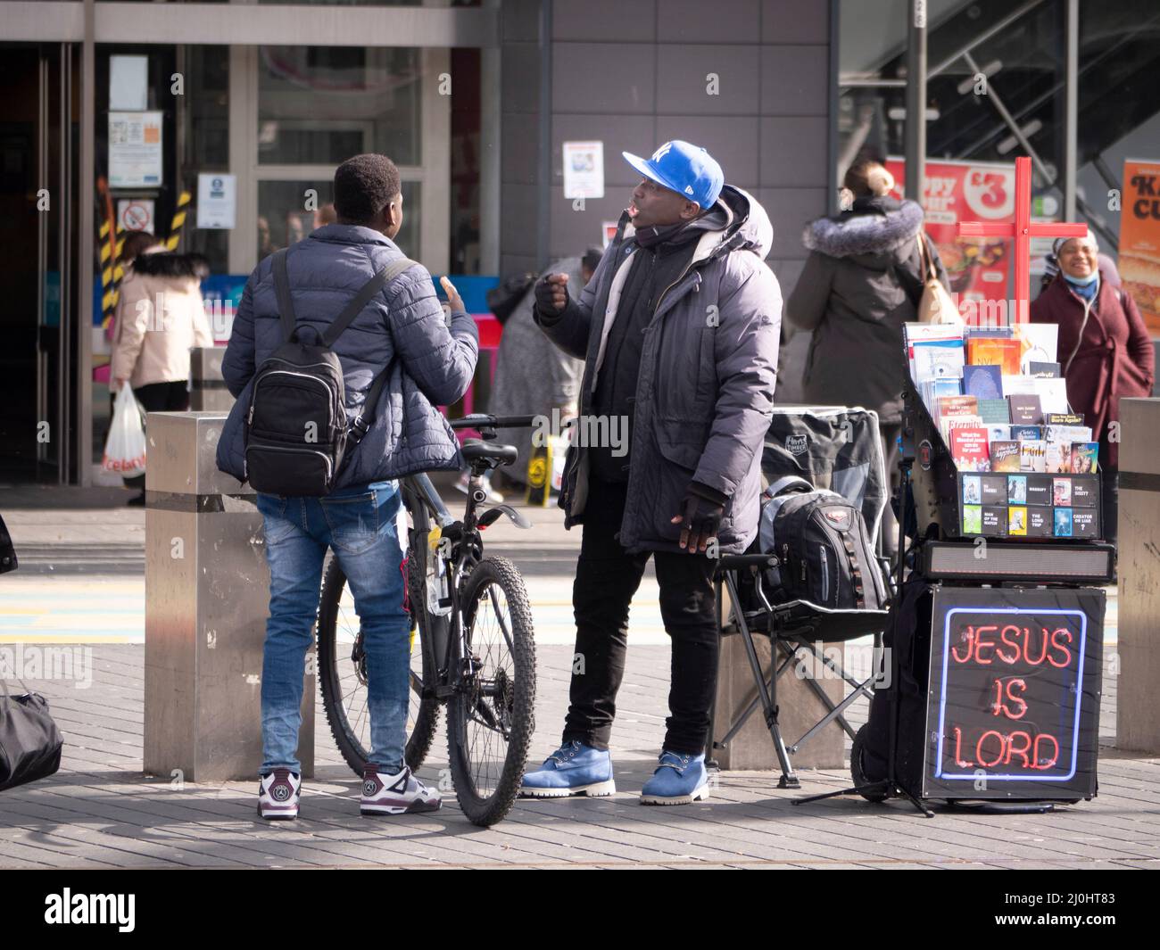 Christian street preacher, with Jesus is Lord neon sign, preaching to ...