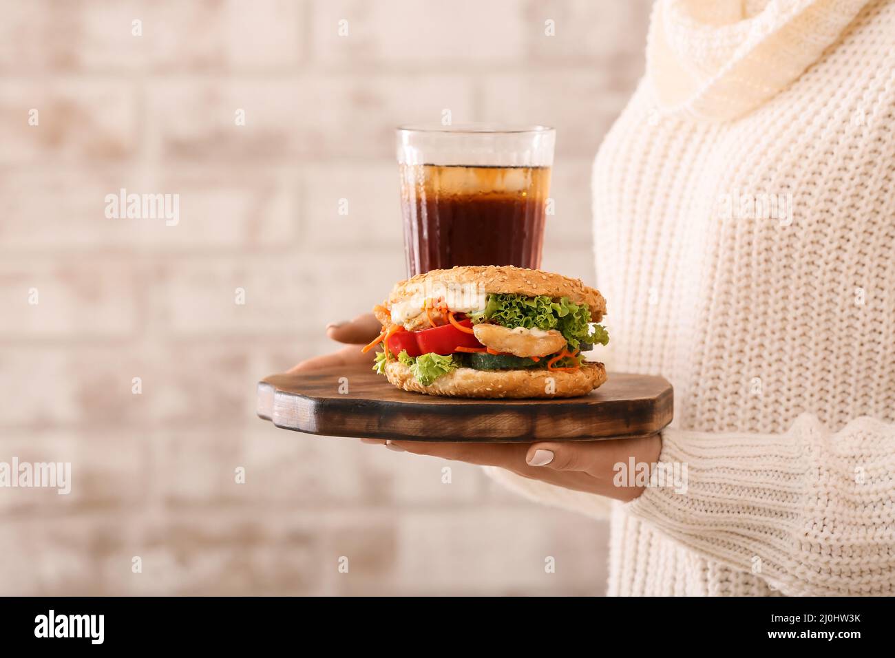 Woman with tasty doner kebab in bun and glass of cola drink on light ...