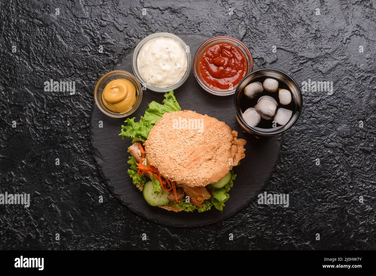 Fresh doner kebab in bun with sauces and glass of cola drink on dark ...