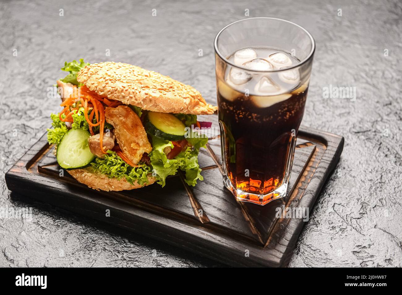 Fresh doner kebab in bun with glass of cola drink on dark background ...