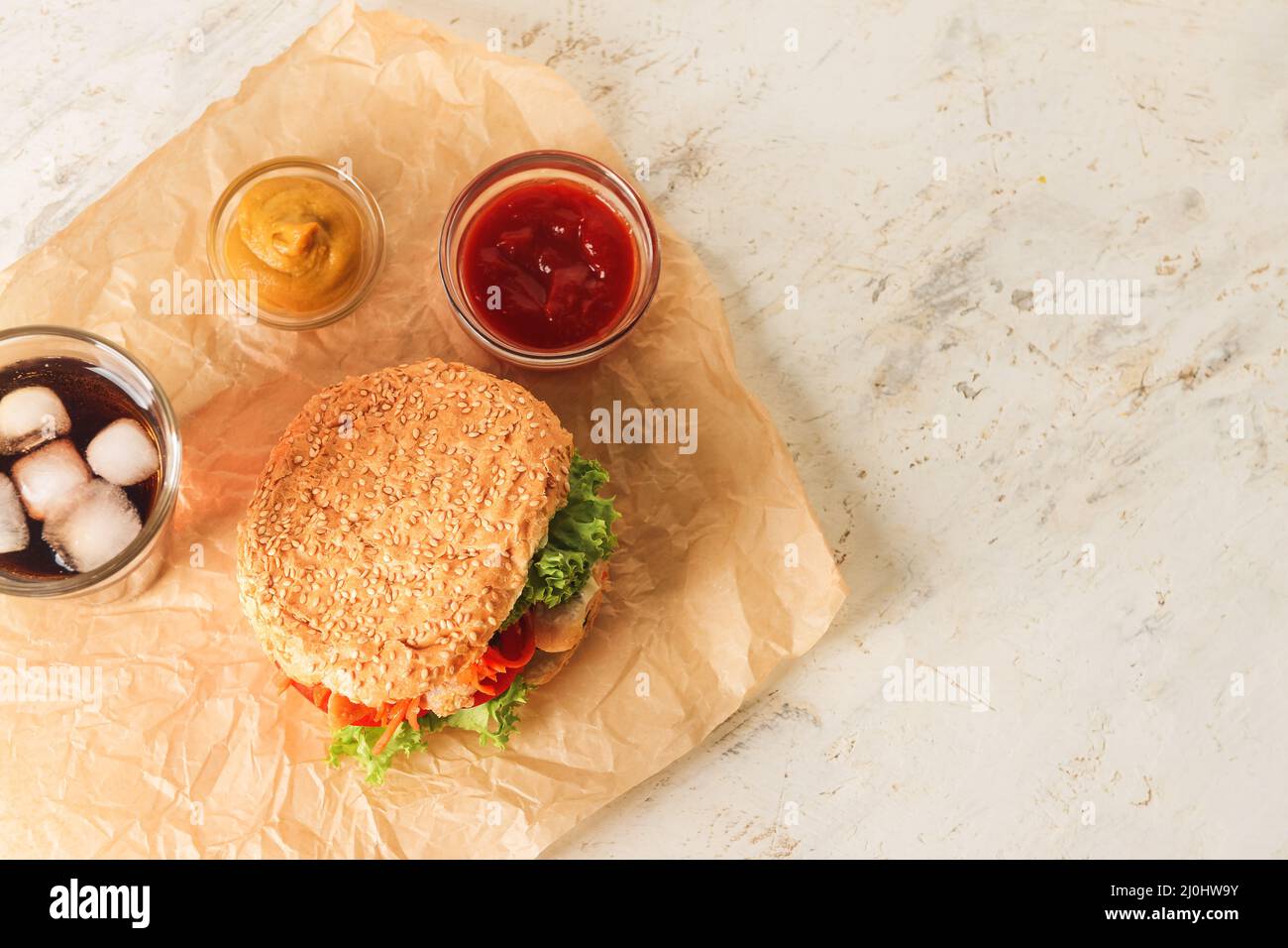 Fresh doner kebab in bun with sauces and glass of cola drink on light ...