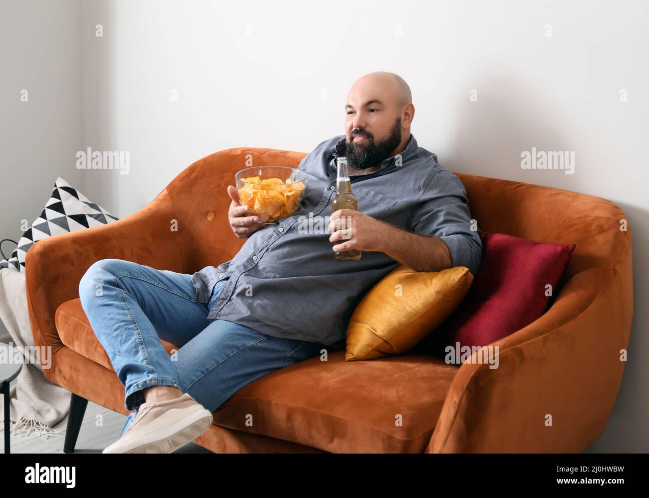 Lazy man drinking beer and eating chips at home Stock Photo - Alamy