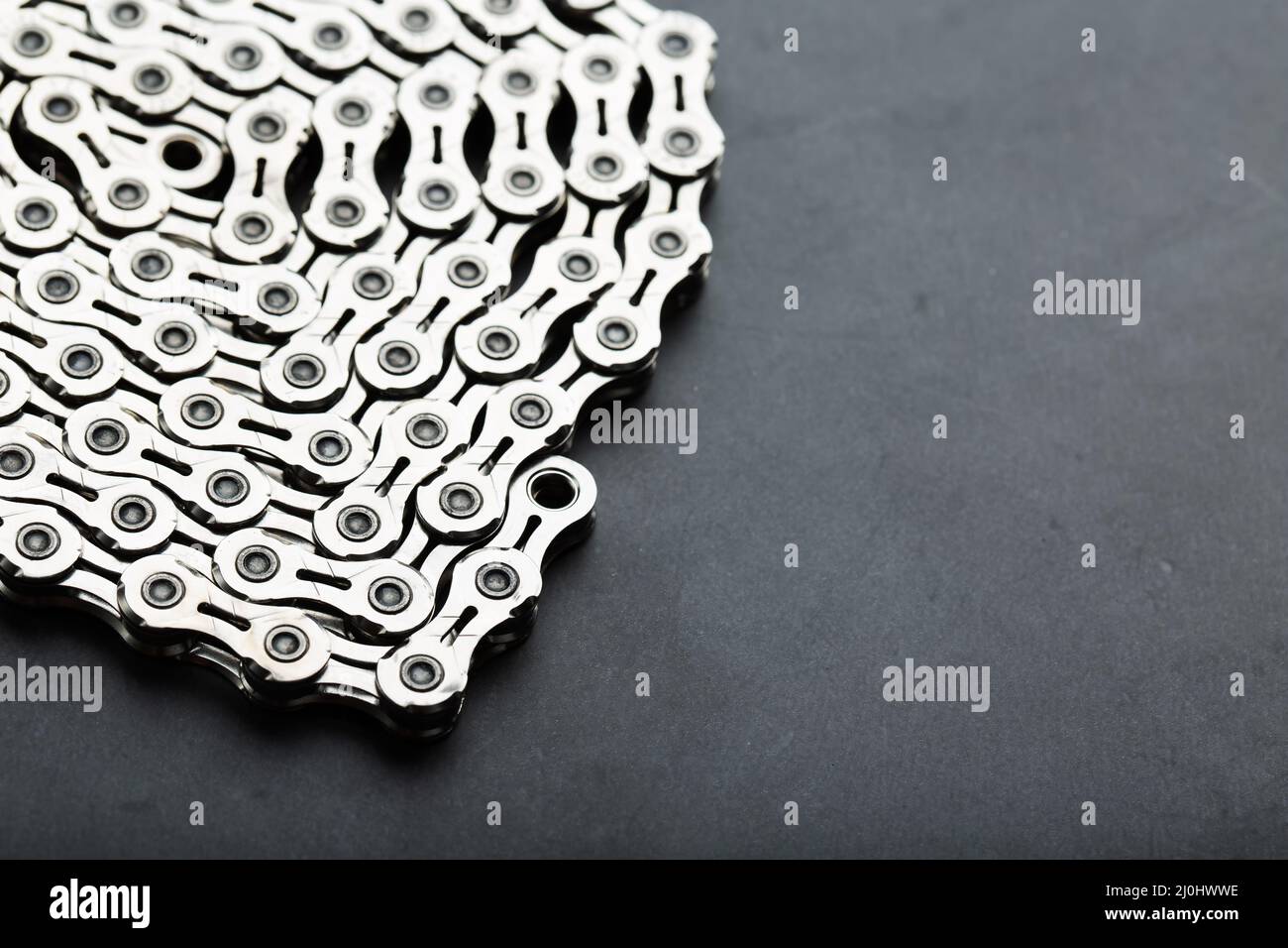 Silver chain of a road bike on a dark textured background with free ...