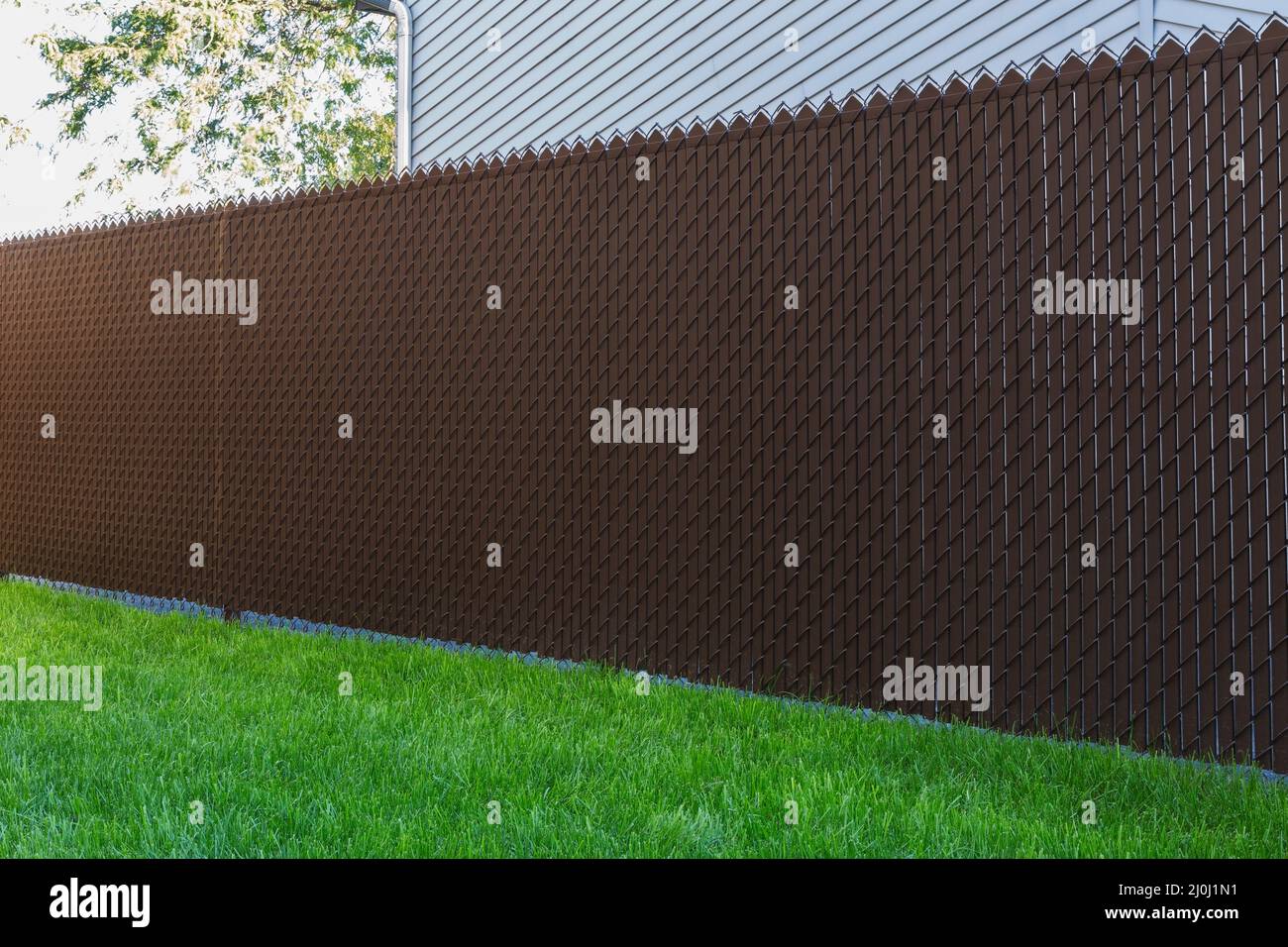 Brown chain-link fence with privacy slats in residential backyard Stock ...