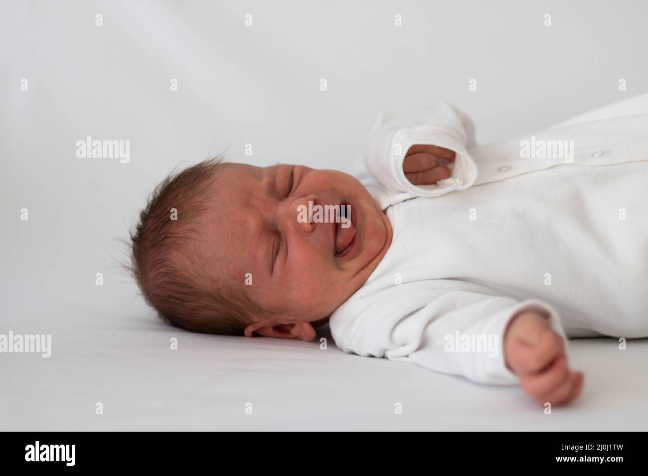 Newborn baby in a white clothes on a white blanket Stock Photo - Alamy