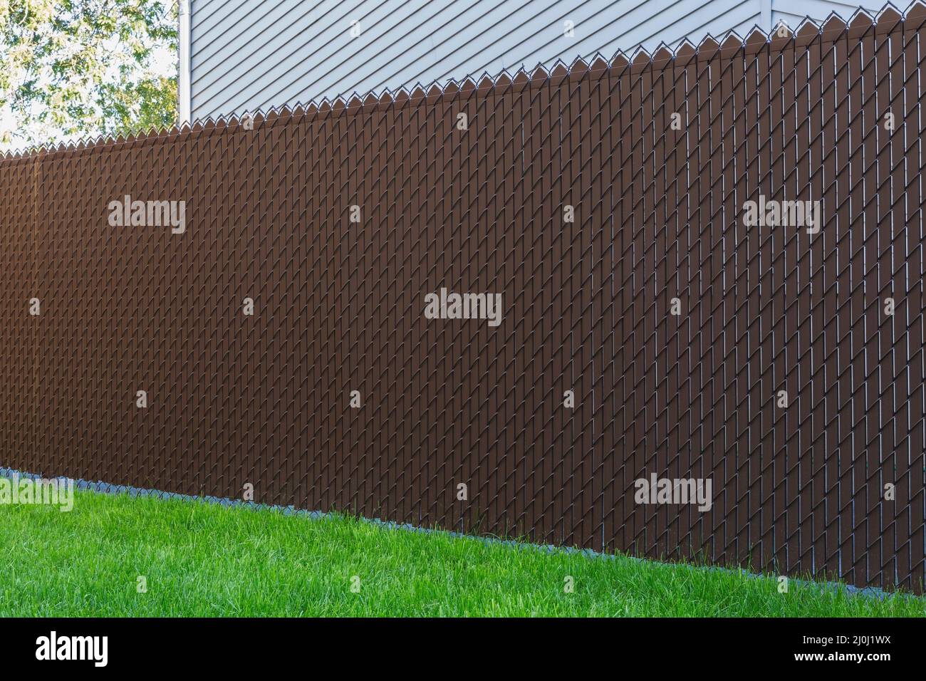 Brown chain-link fence with privacy slats in residential backyard Stock ...