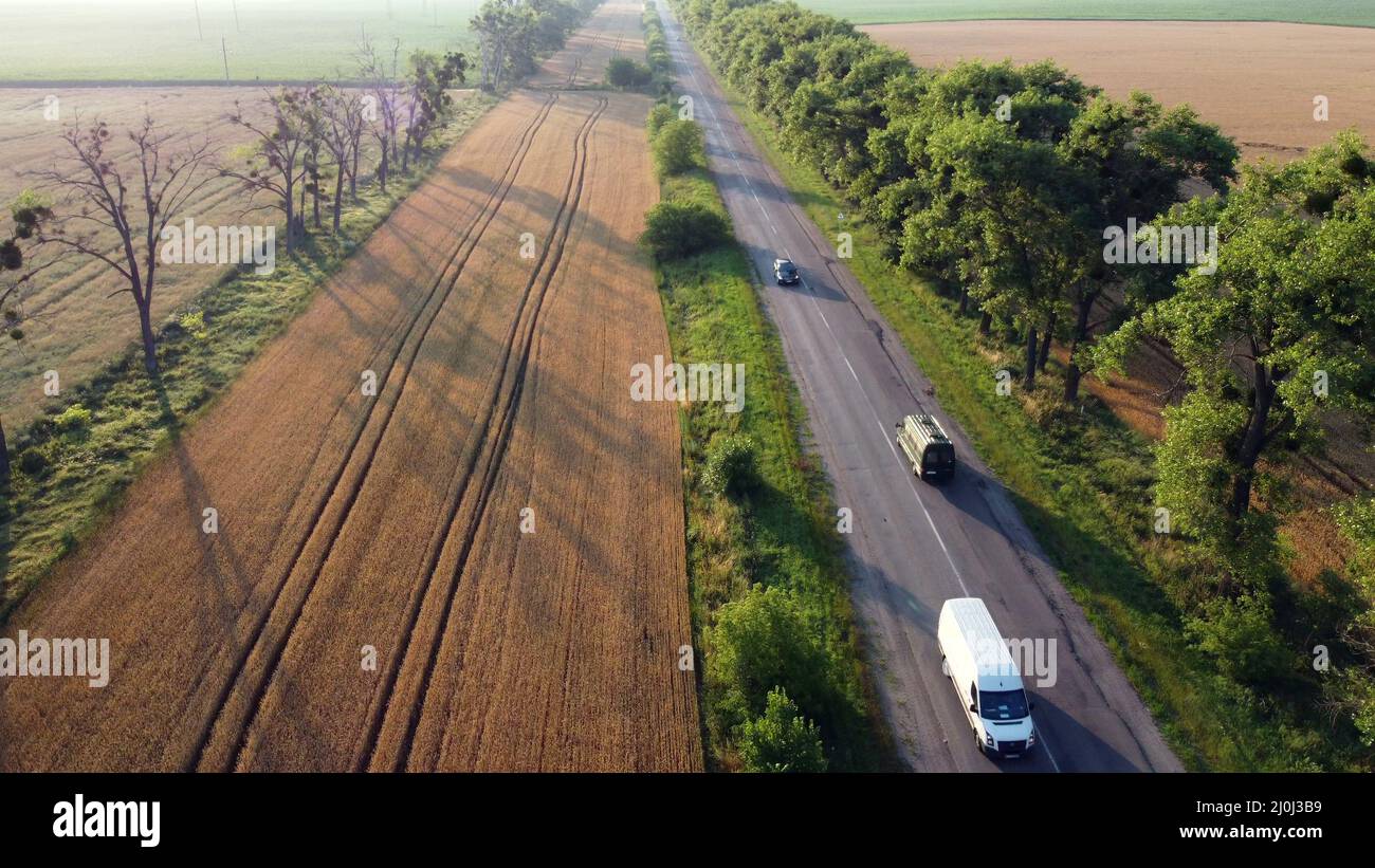 Aerial drone view flight over highway wheat field and green trees at ...