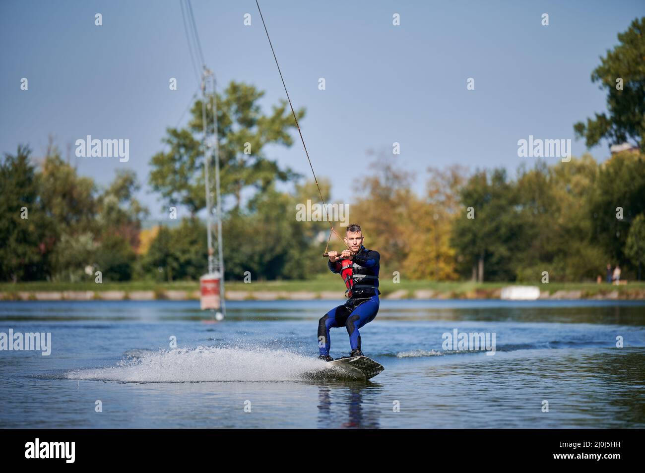 Wakeboarder surfing on lake. Young man surfer having fun wakeboarding ...