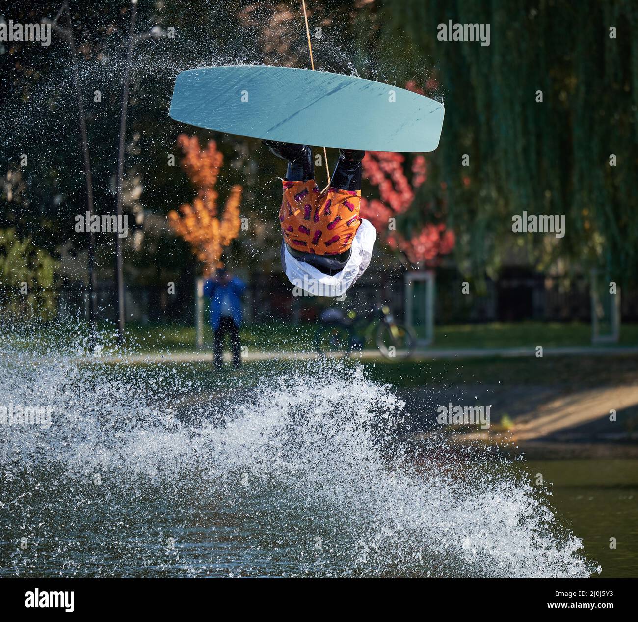 Wakeboarder making tricks while wakeboarding on lake. Young man surfer ...