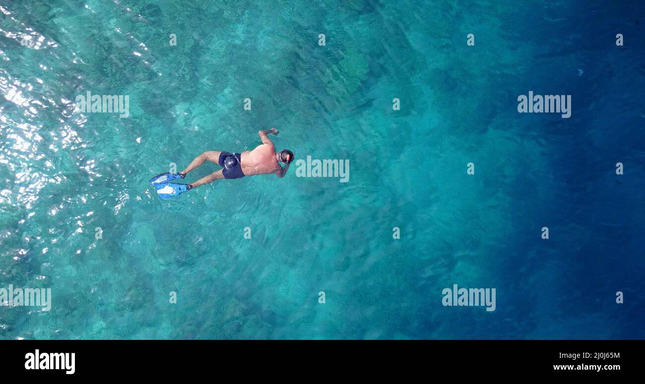 Top view of a man swimming with flippers in Rasdhoo Island, The ...