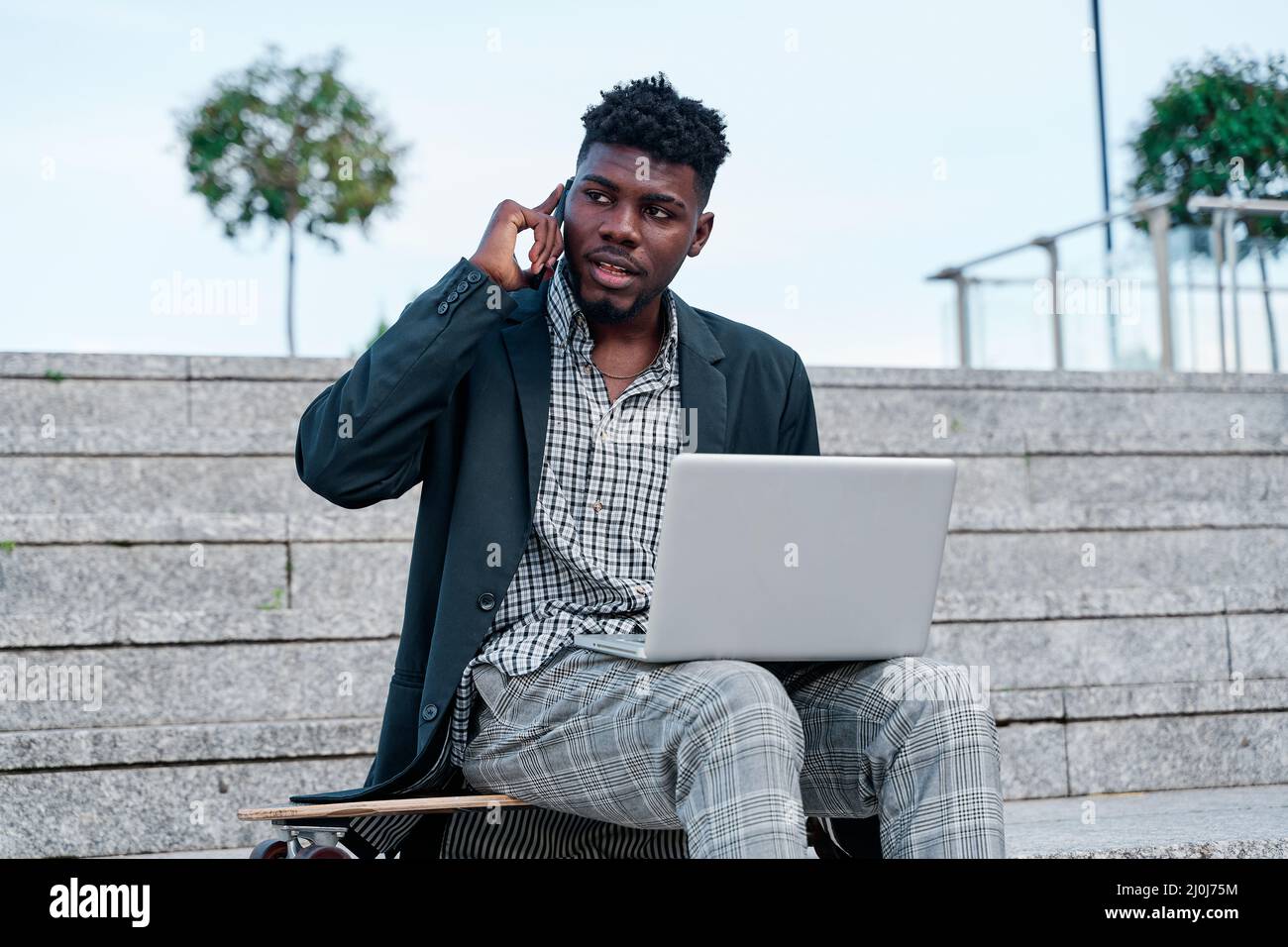 Pensive African-American student in suit jacket sitting with laptop ...