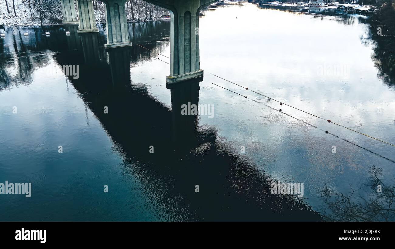 Snow covers the land with this bridge extending over the calm river ...