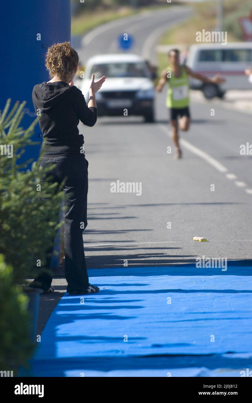 Woman cheering for the runner at the end line of the race Stock Photo ...