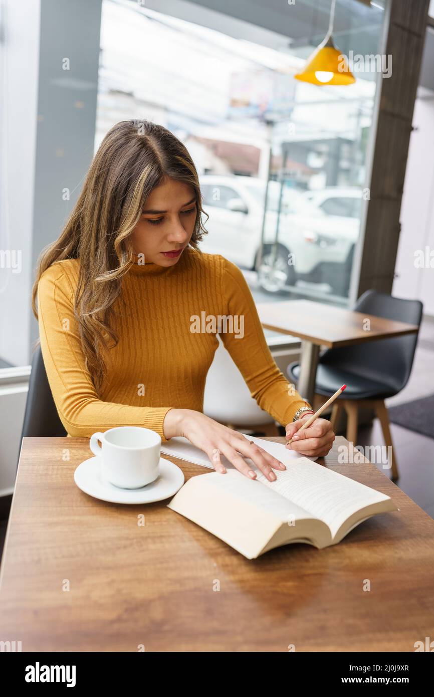 writing on a book with a pencil a beautiful young latin woman with long ...