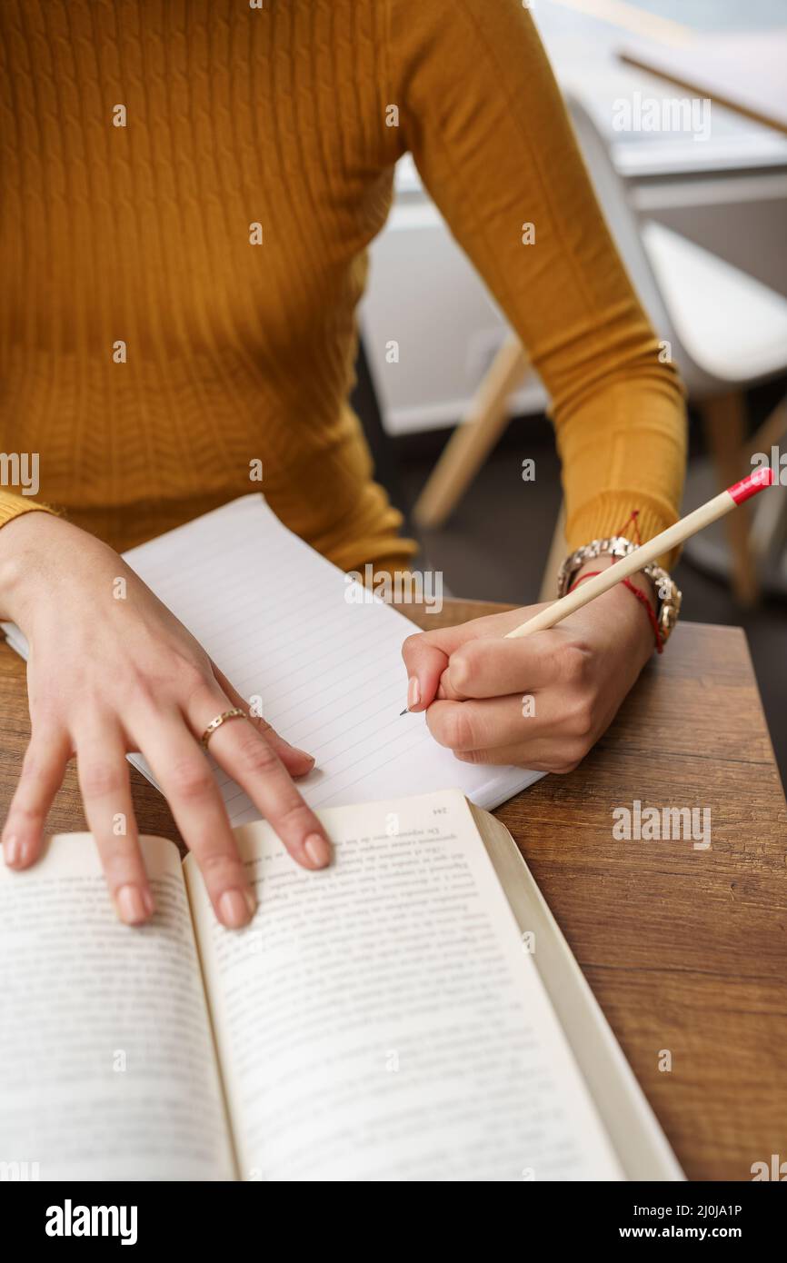 details of the hand of a person holding a pencil to make notes on a ...