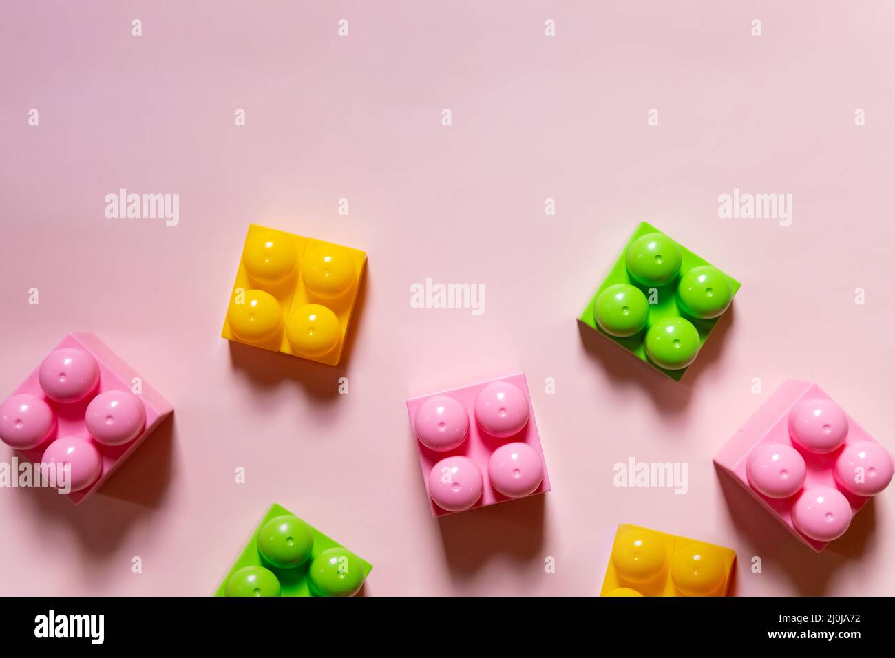 Colorful plastic building blocks flat lay. Yellow background. Child ...