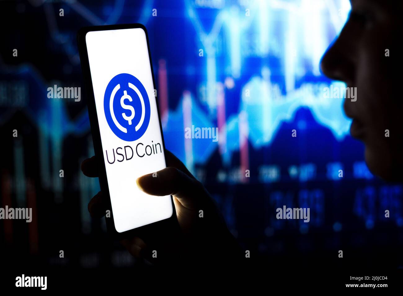 In this photo illustration, a woman holds a smartphone with the USD Coin (USDC) logo displayed ...