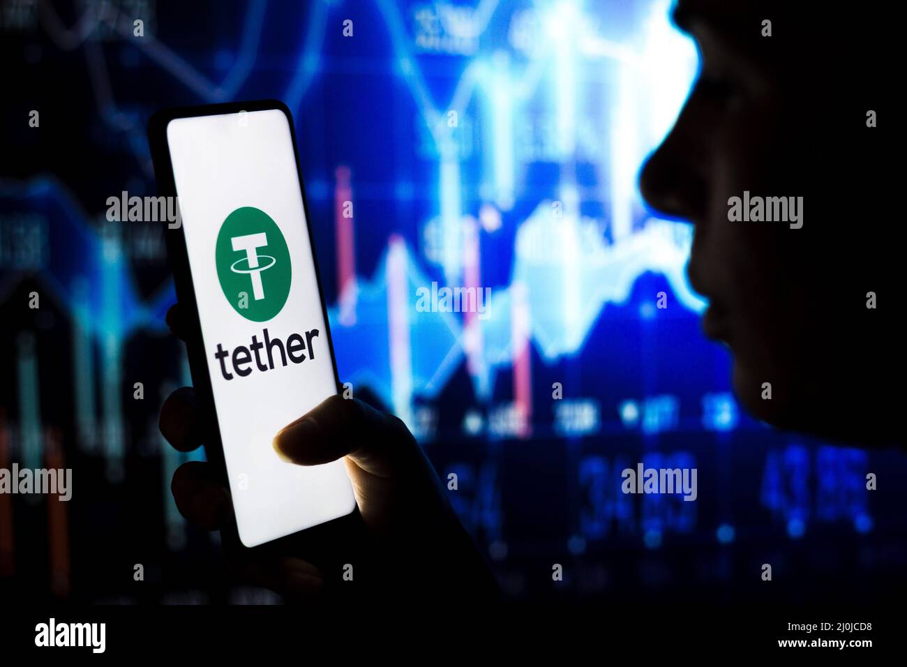 In this photo illustration, a woman holds a smartphone with the Tether ...