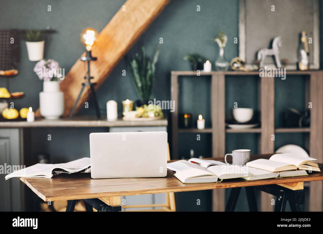 Open textbook with pen, laptop, stack of uncovered books and cup of ...