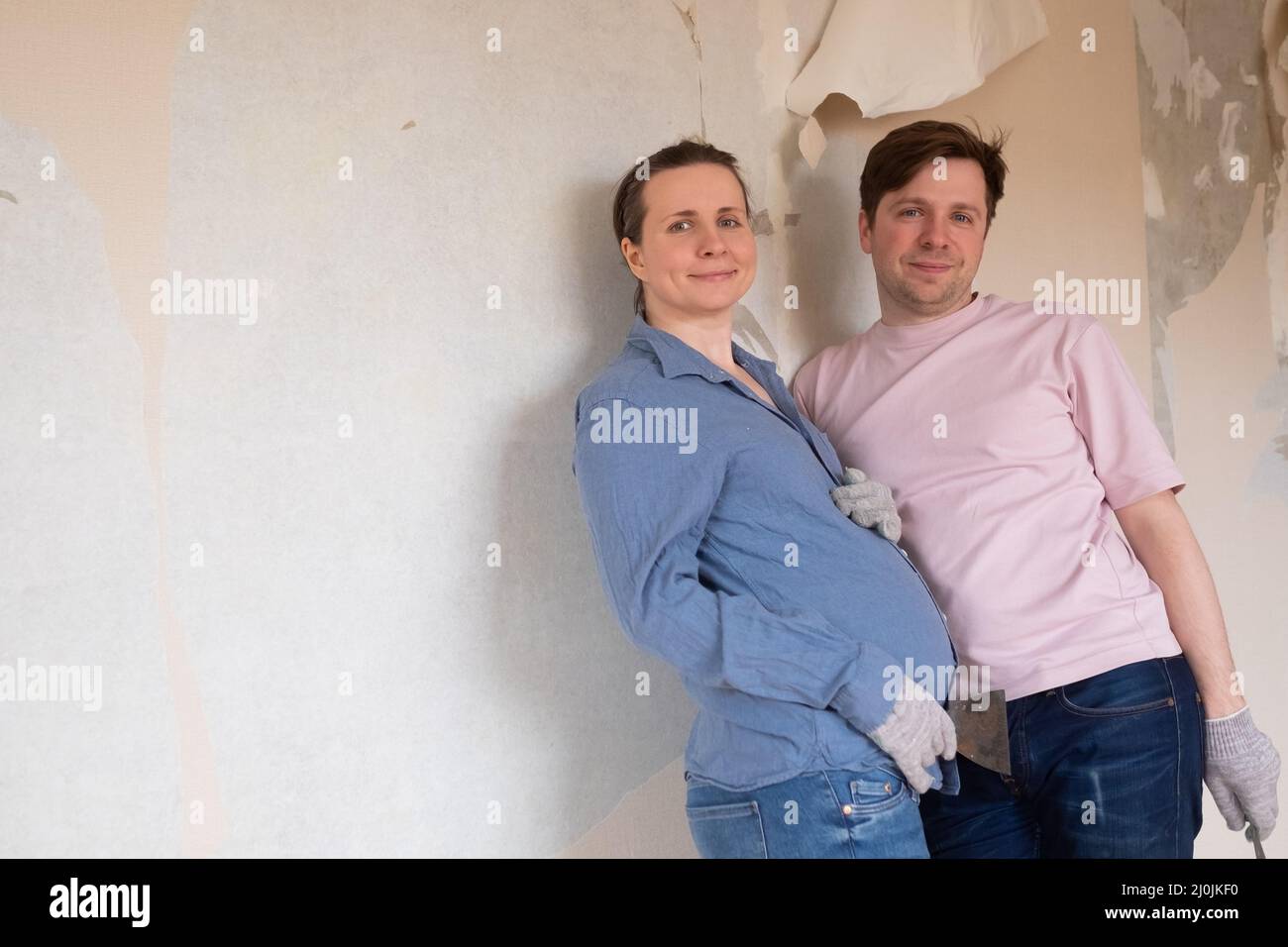 Young caucasian couple removing old wallpaper from walls preparing for ...