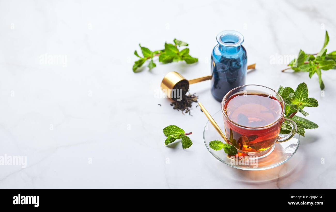 Black tea in glass transparent mug with mint leaves. Soothing tea, anti ...