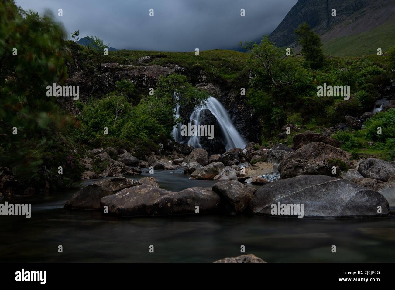 Flowing waterfall into a stream in a rural gloomy area of England Stock ...