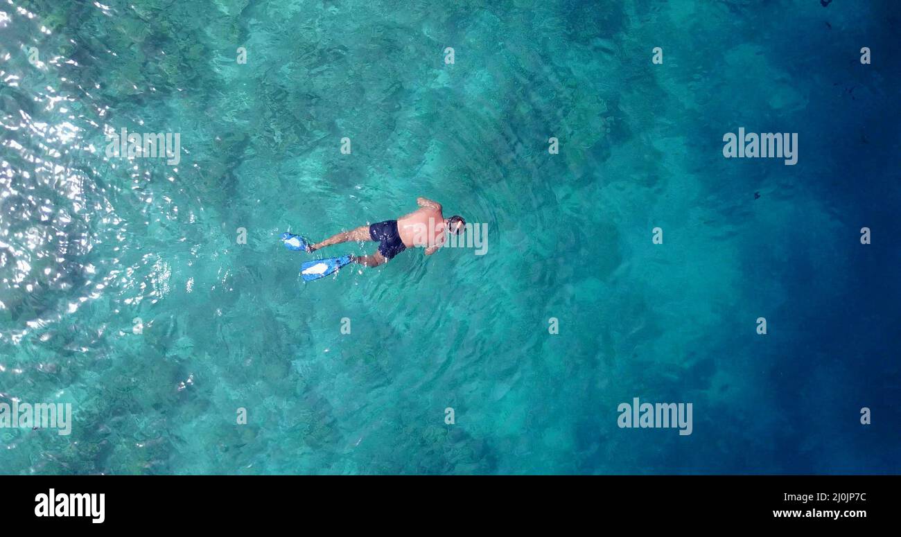 Aerial top view of a diver swimming in the ocean in Rasdhoo Island, the ...