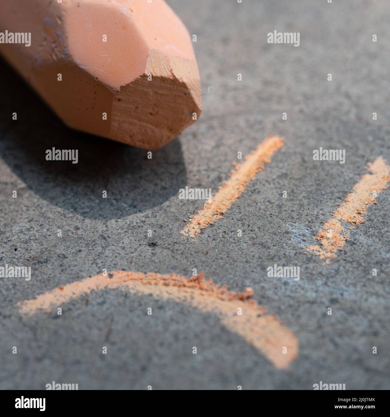 Closeup of orange chalk with a sad face drawn on the asphalt Stock ...