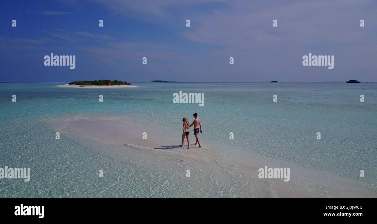 Panoramic view of a couple walking on the sandy beach in Rasdhoo Island ...