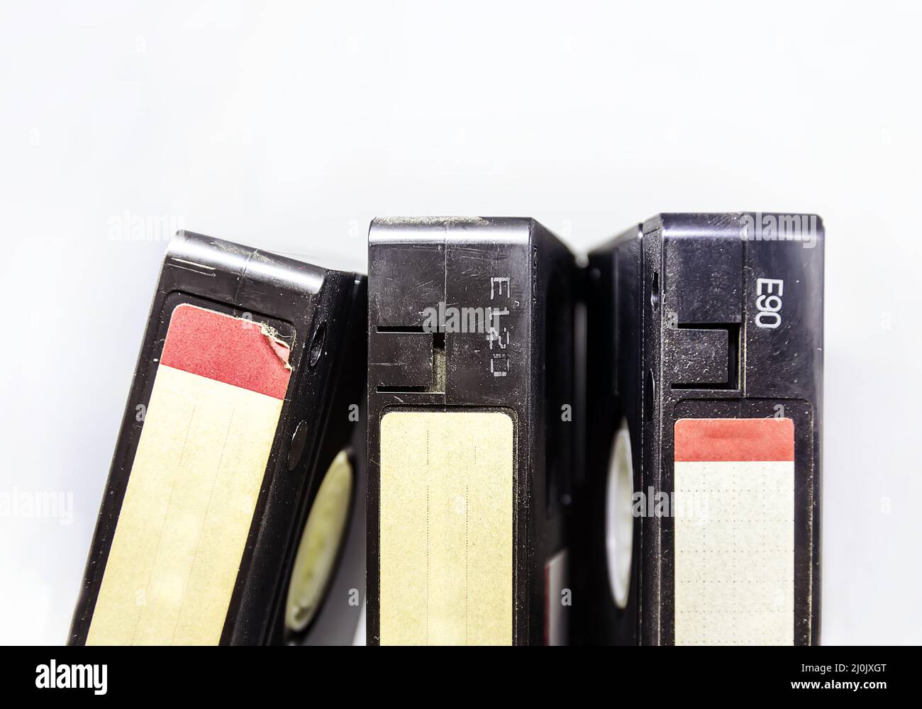 Three VHS video cassettes stacked vertically with blank label isolated ...