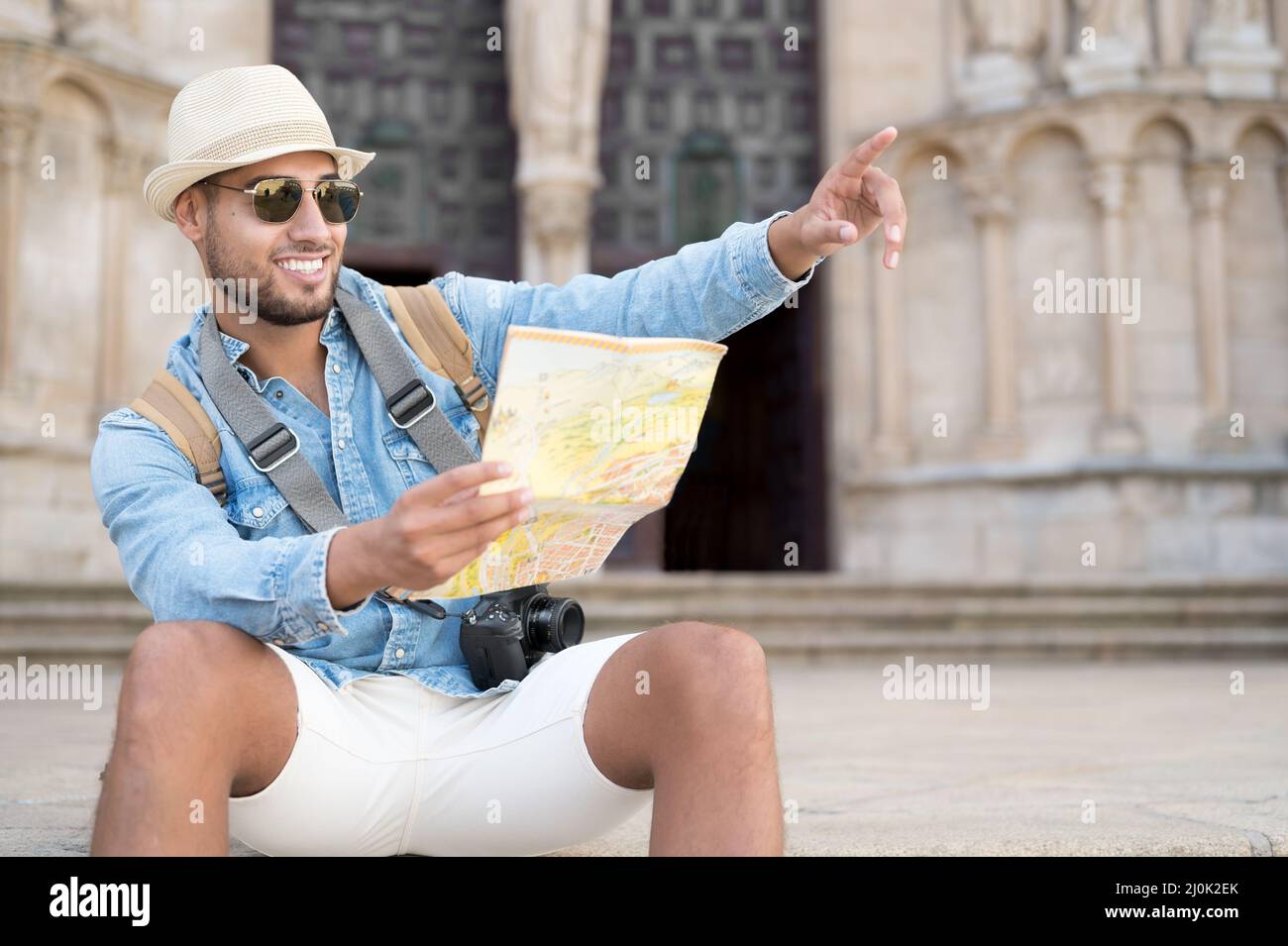Handsome tourist man look at map while pointing finger in the direction ...