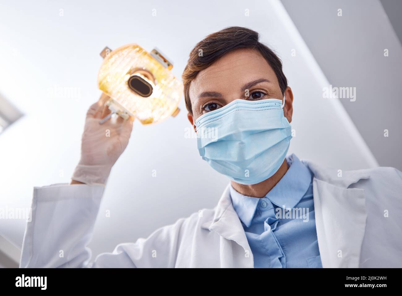 Open wide.... Low angle shot of a dentist getting ready to perform a ...