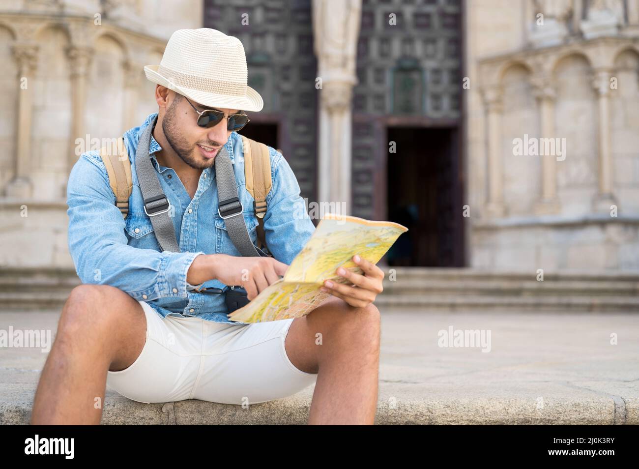 Handsome tourist man pointing at map searching the direction of ...