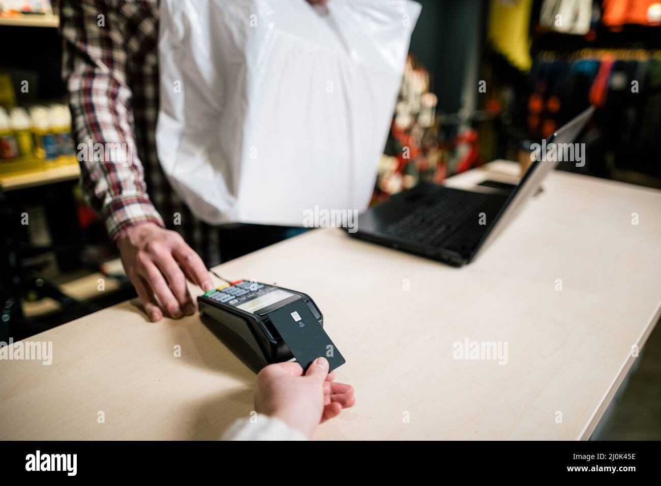 Customer paying by card at store. Seller uses credit card terminal to ...