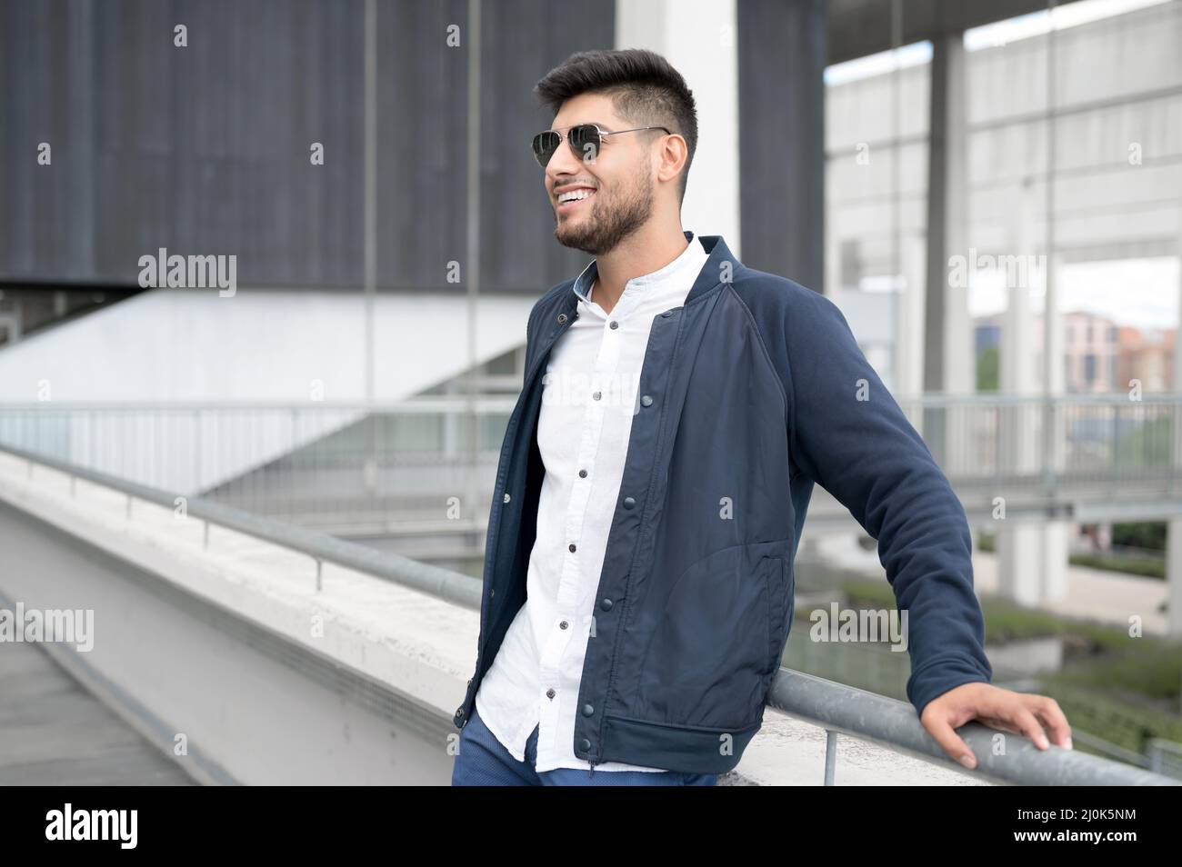 Portrait of a young confident smiling man standing beside modern ...