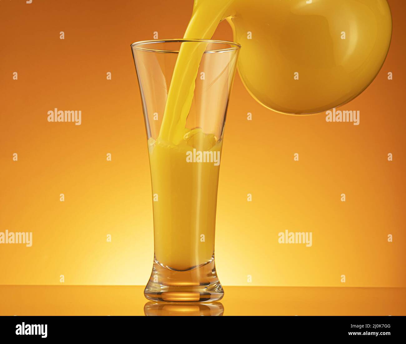 Orange juice pouring into glass with splash Stock Photo - Alamy