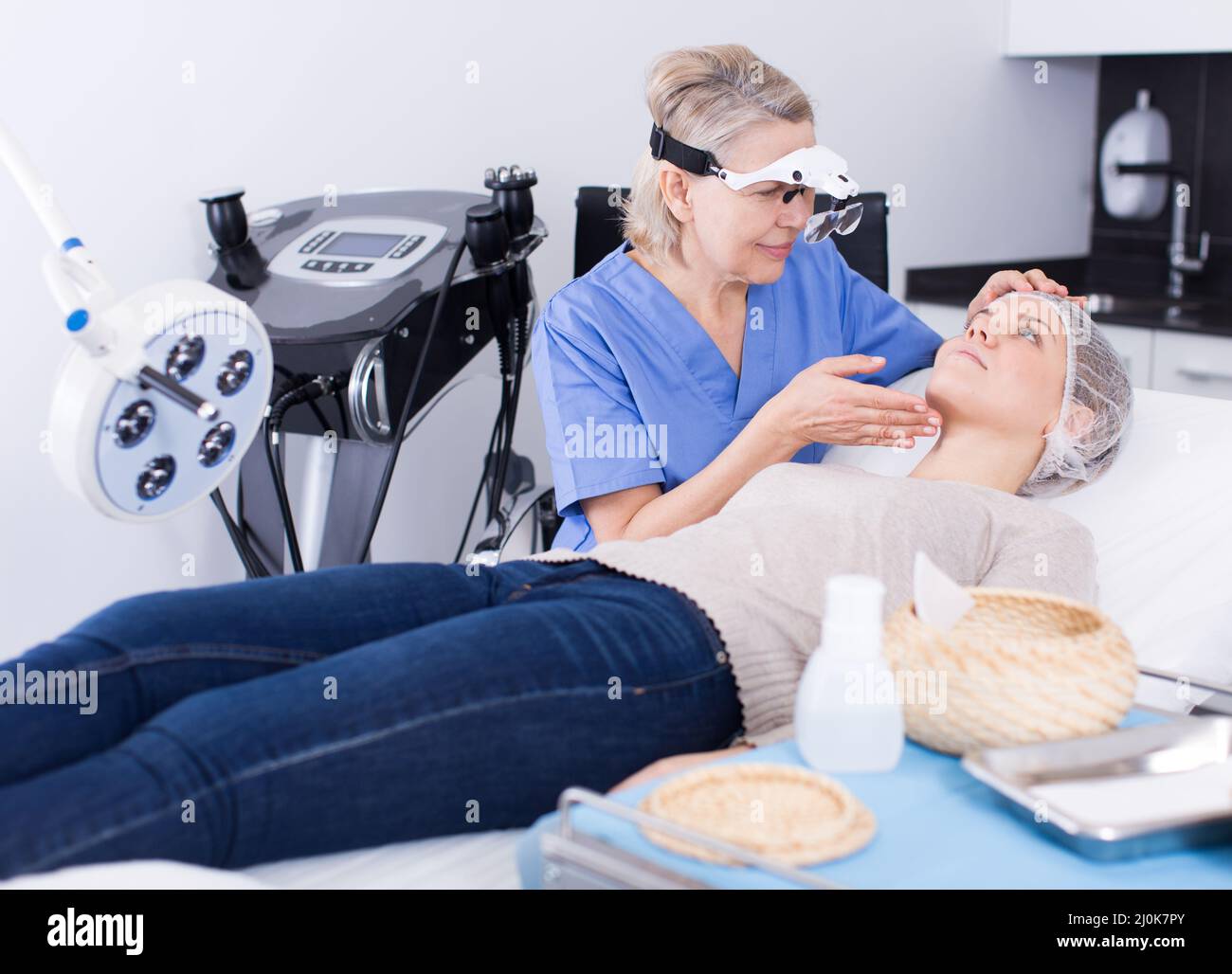 Cosmetician examining face skin of girl Stock Photo - Alamy