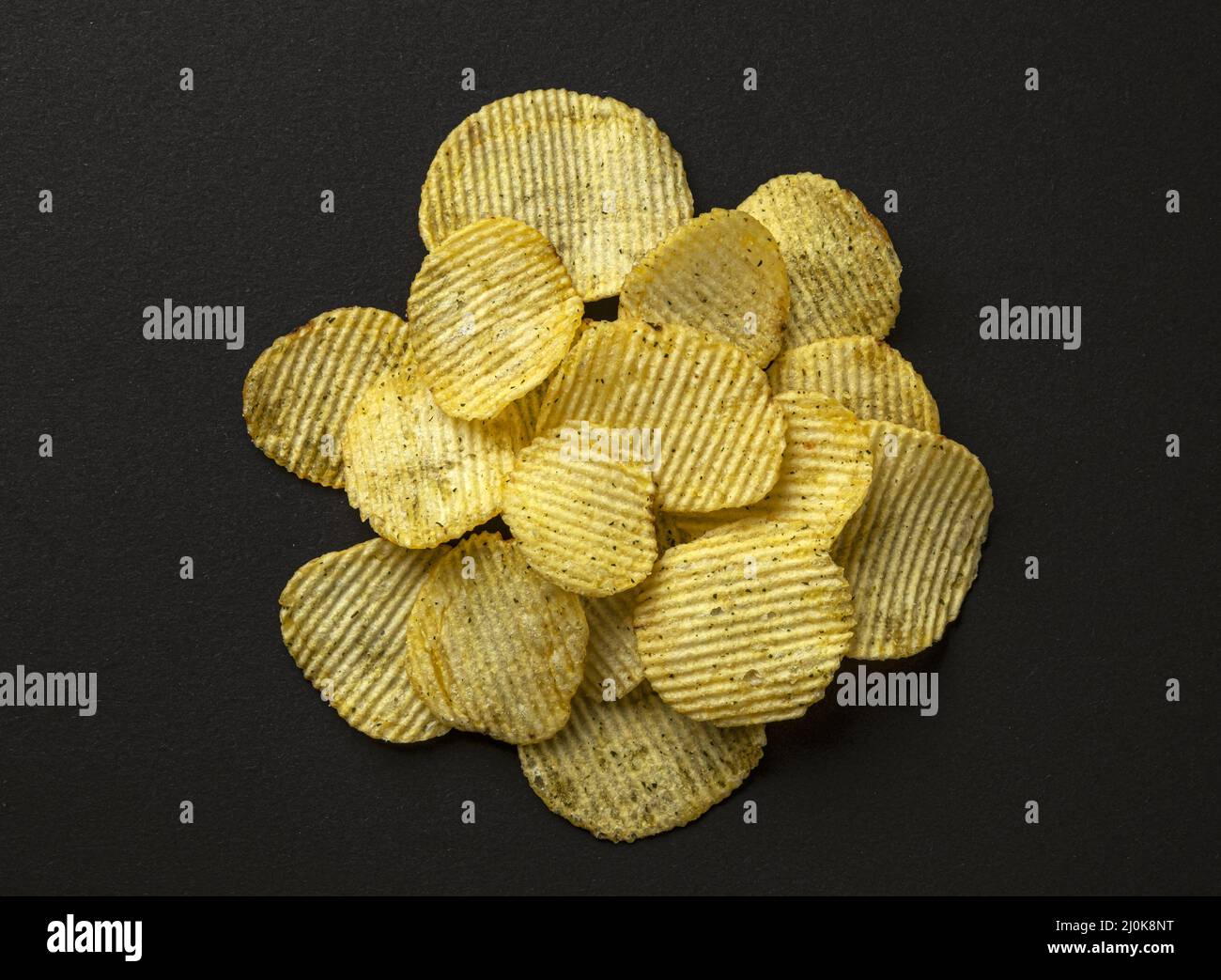 Ridged potato chips on black background Stock Photo - Alamy