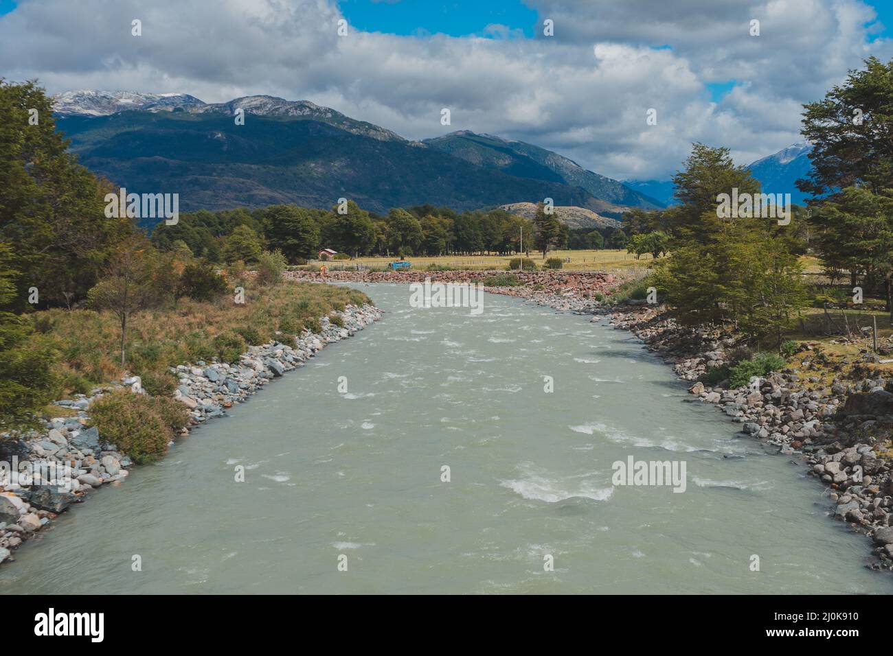 River surrounded by trees and mountains under a cloudy sky Stock Photo ...