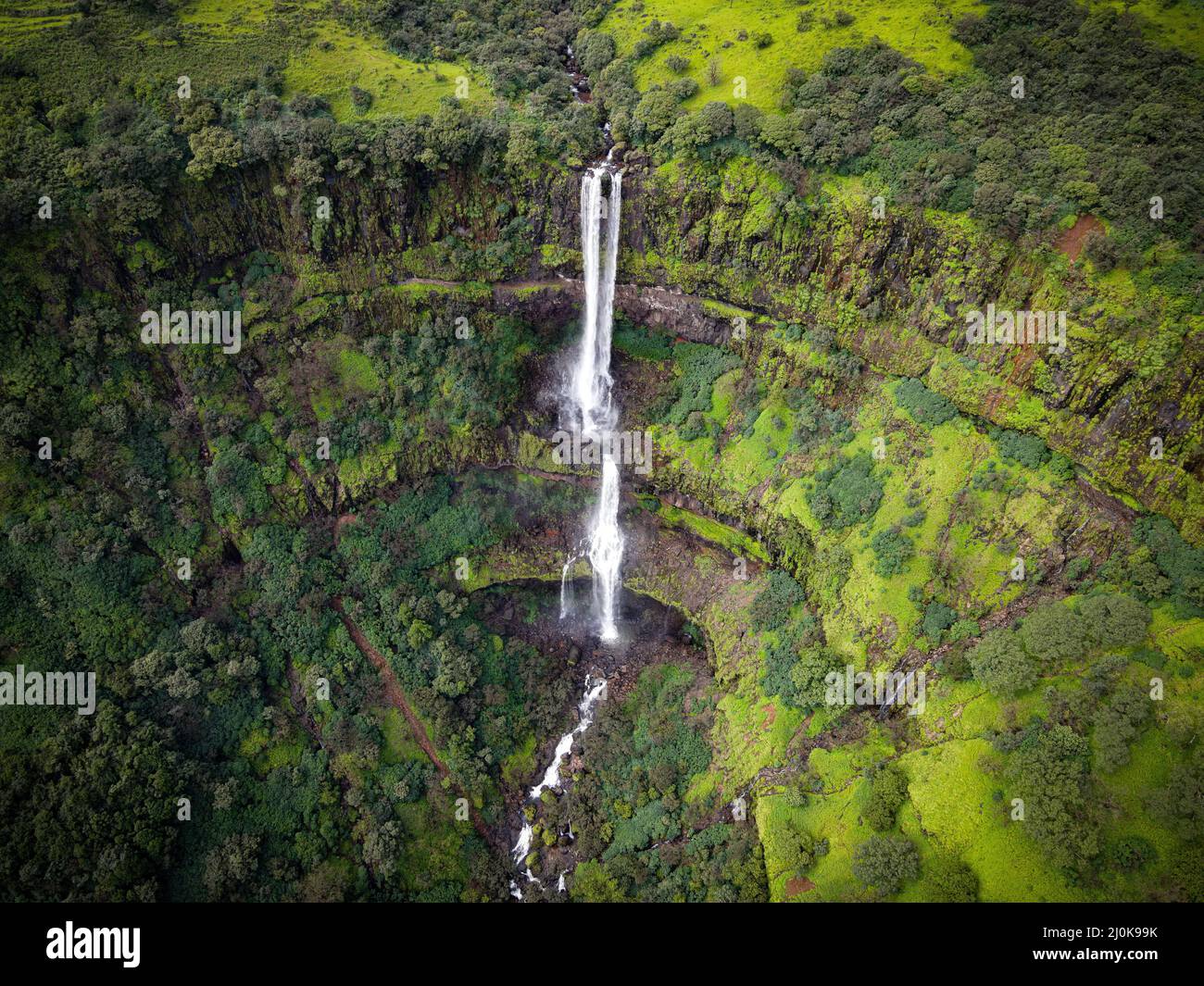 Aerial view of a scenic waterfall flowing down a green cliff Stock ...