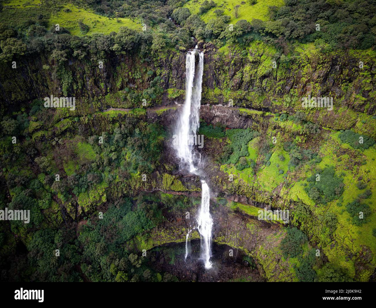 Aerial view of a scenic waterfall flowing down a green cliff Stock ...